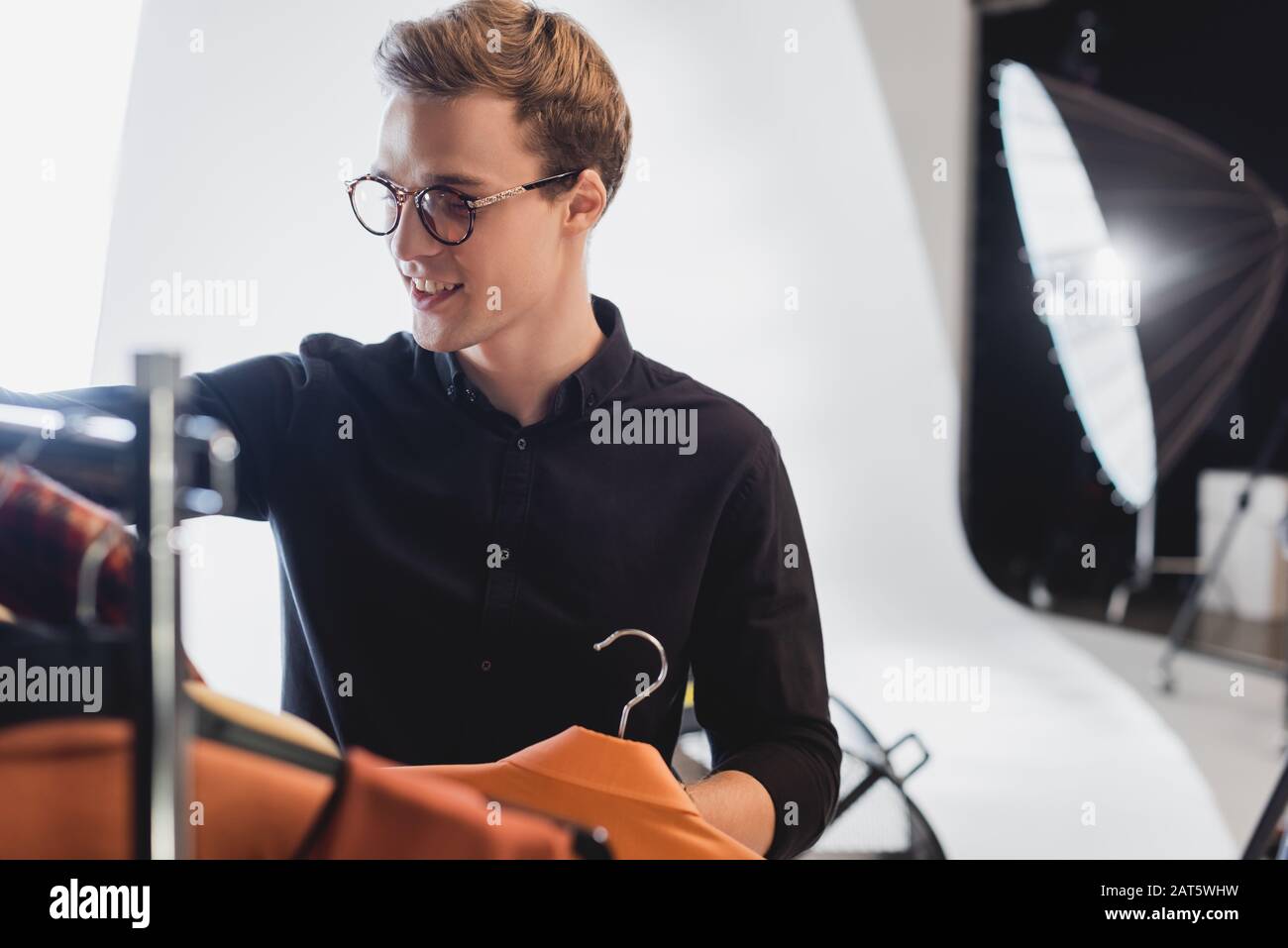 smiling stylist choosing clothes for photo shoot on backstage Stock ...