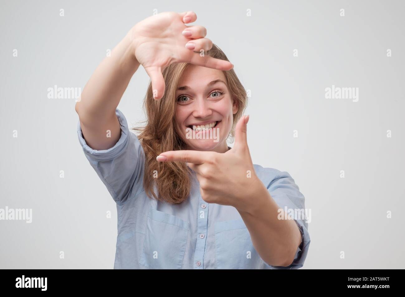 Young beautiful woman making frame with her hands smiling over white ...