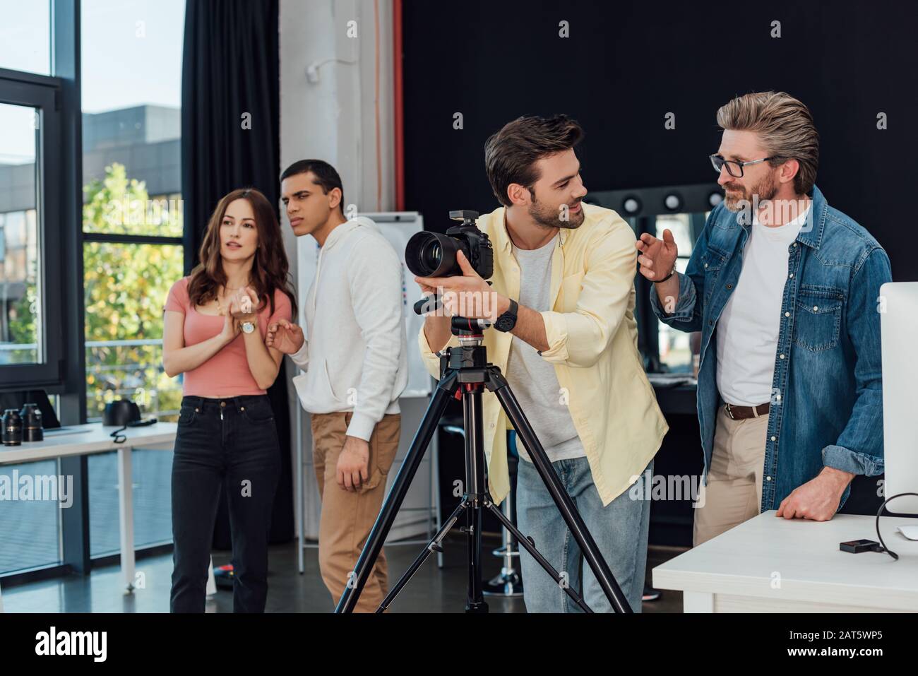 photographer touching digital camera near art director in glasses and ...