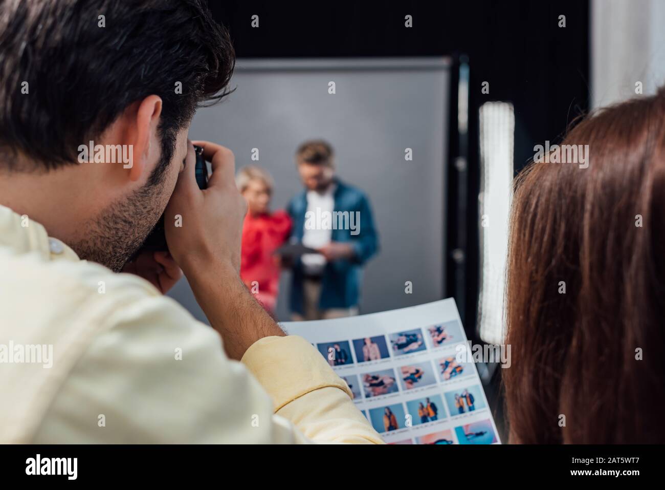 back view of photographer taking photo of model and art director in ...