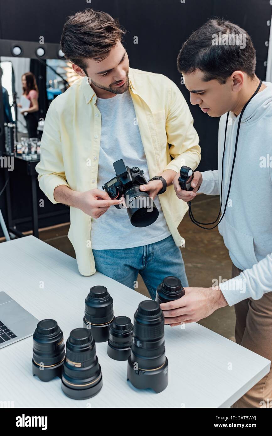 handsome art director standing near photographer and holding photo lens ...
