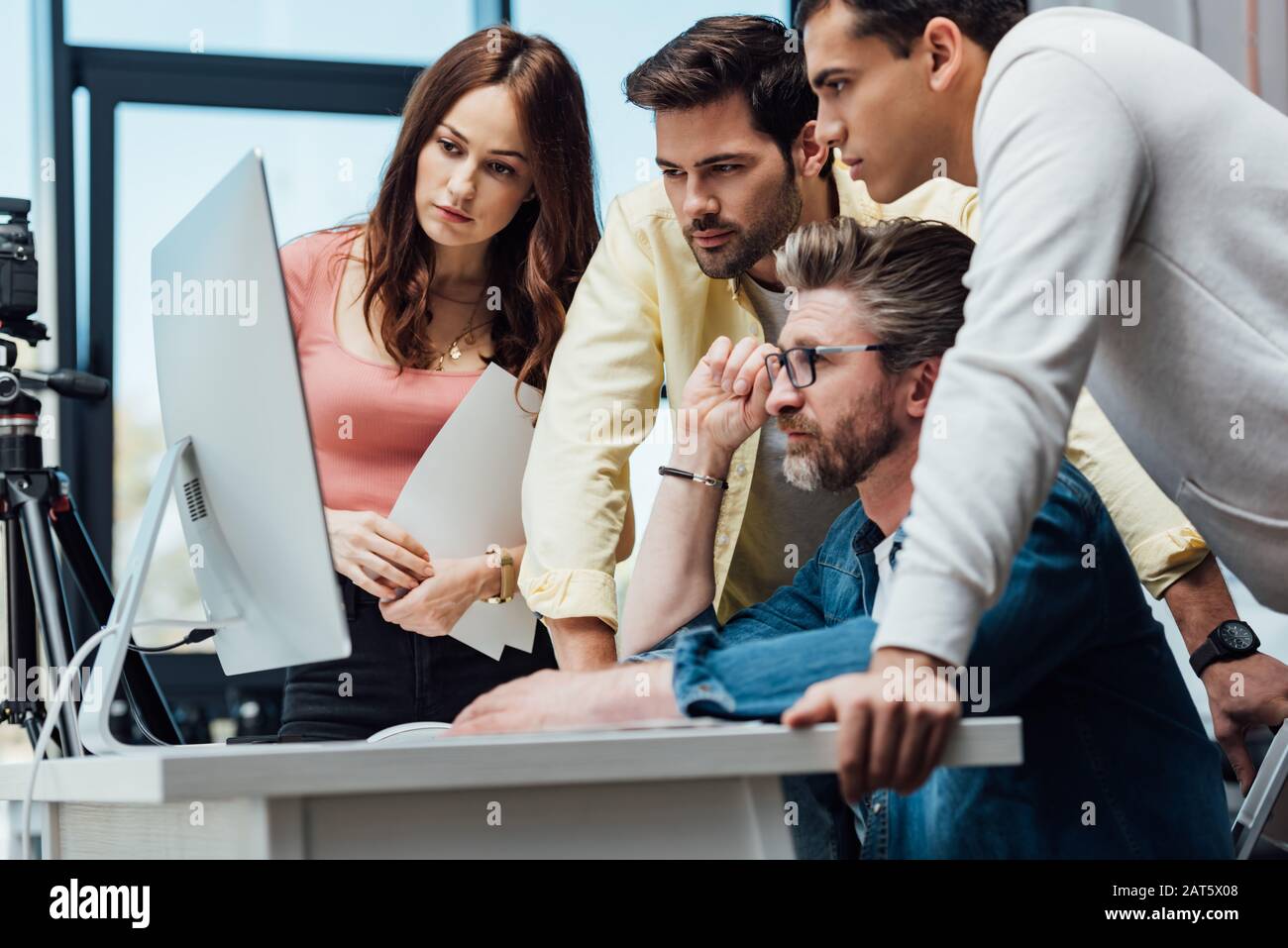 bearded creative director touching glasses and looking at computer ...