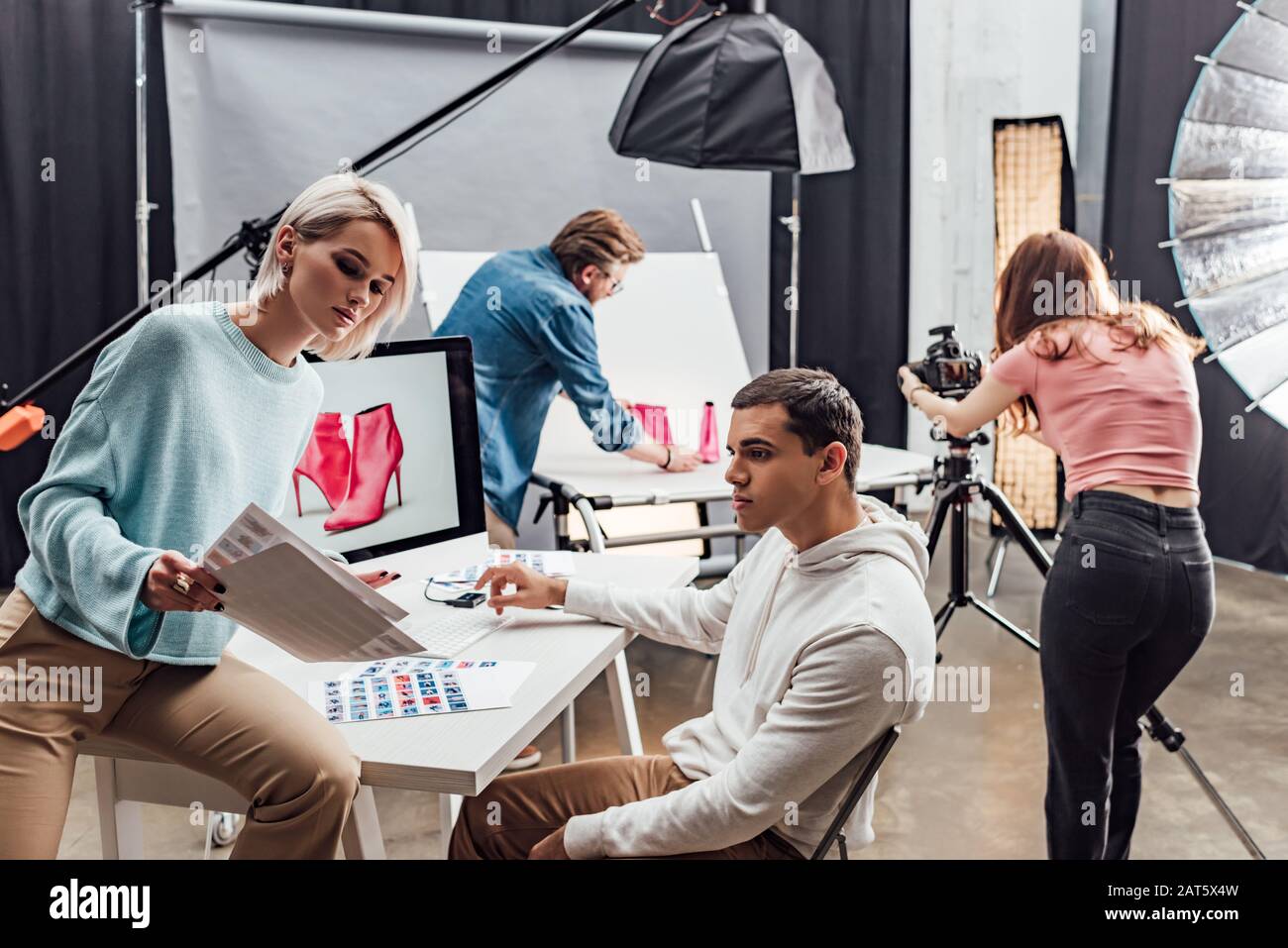 attractive art director looking at photos near computer monitor and ...