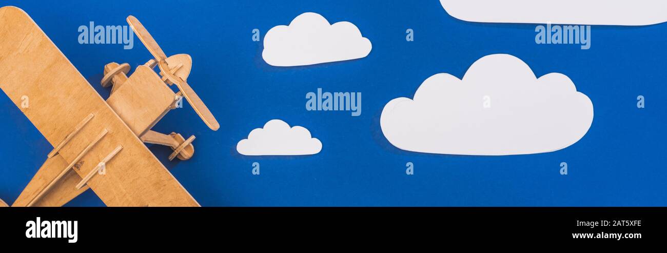 top view of wooden plane in blue sky with paper cut white clouds ...
