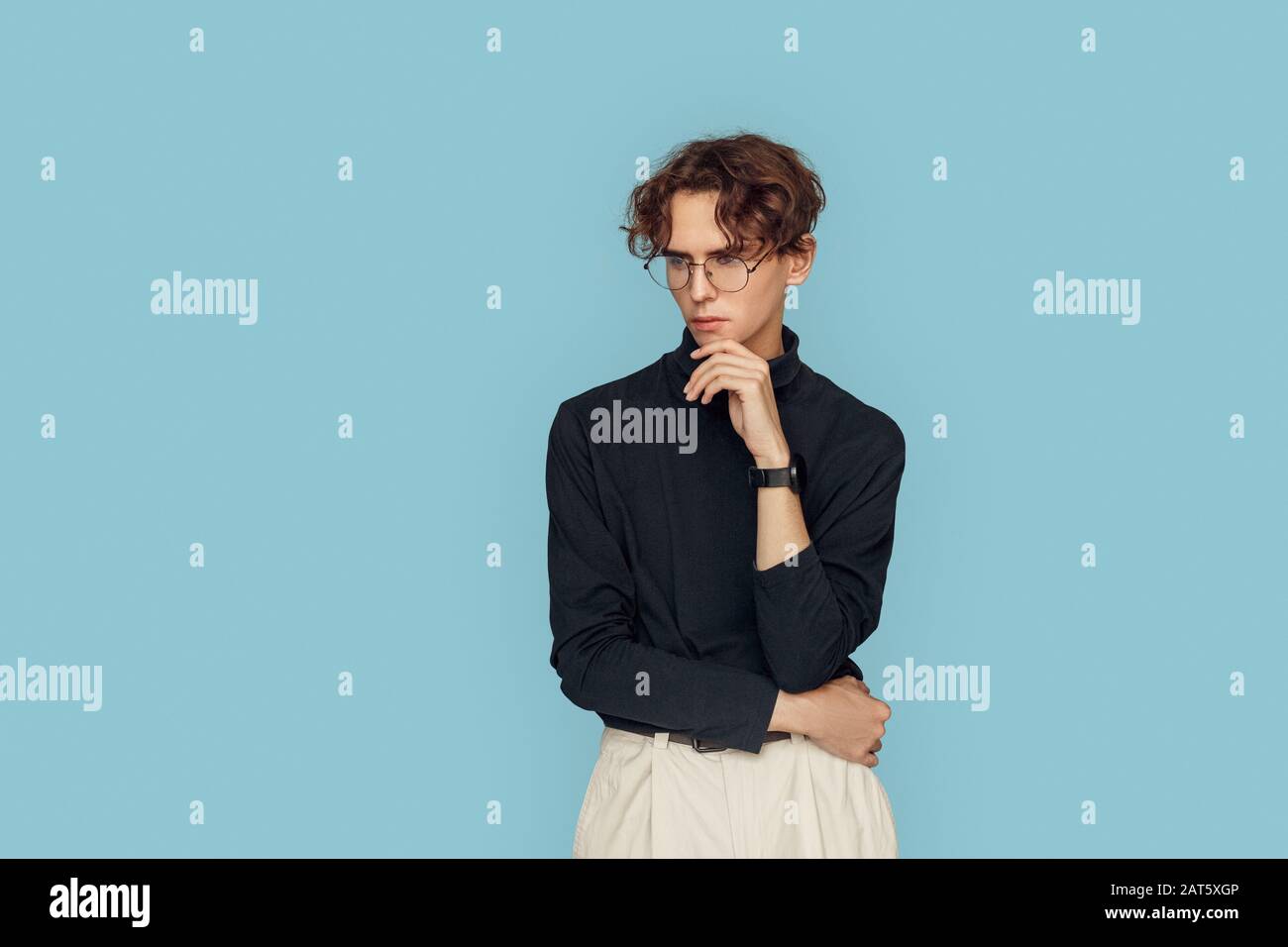 Freestyle. Man in glasses standing isolated on gray touching chin ...