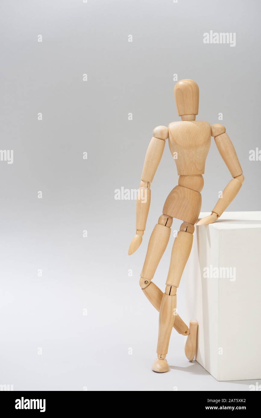 Wooden doll beside white cube on grey background Stock Photo - Alamy