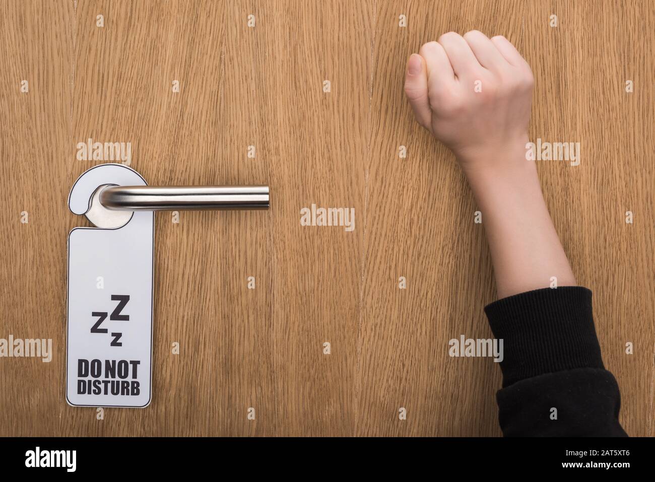 cropped view of woman knocking at door with do no disturb sign Stock ...