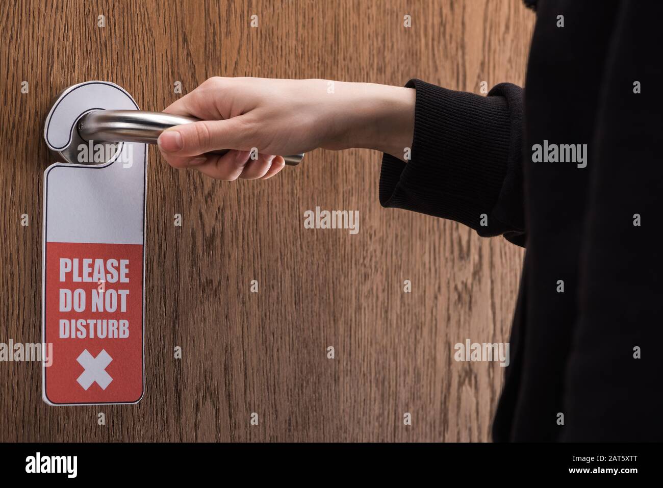 partial view of woman holding door handle with please do no disturb ...