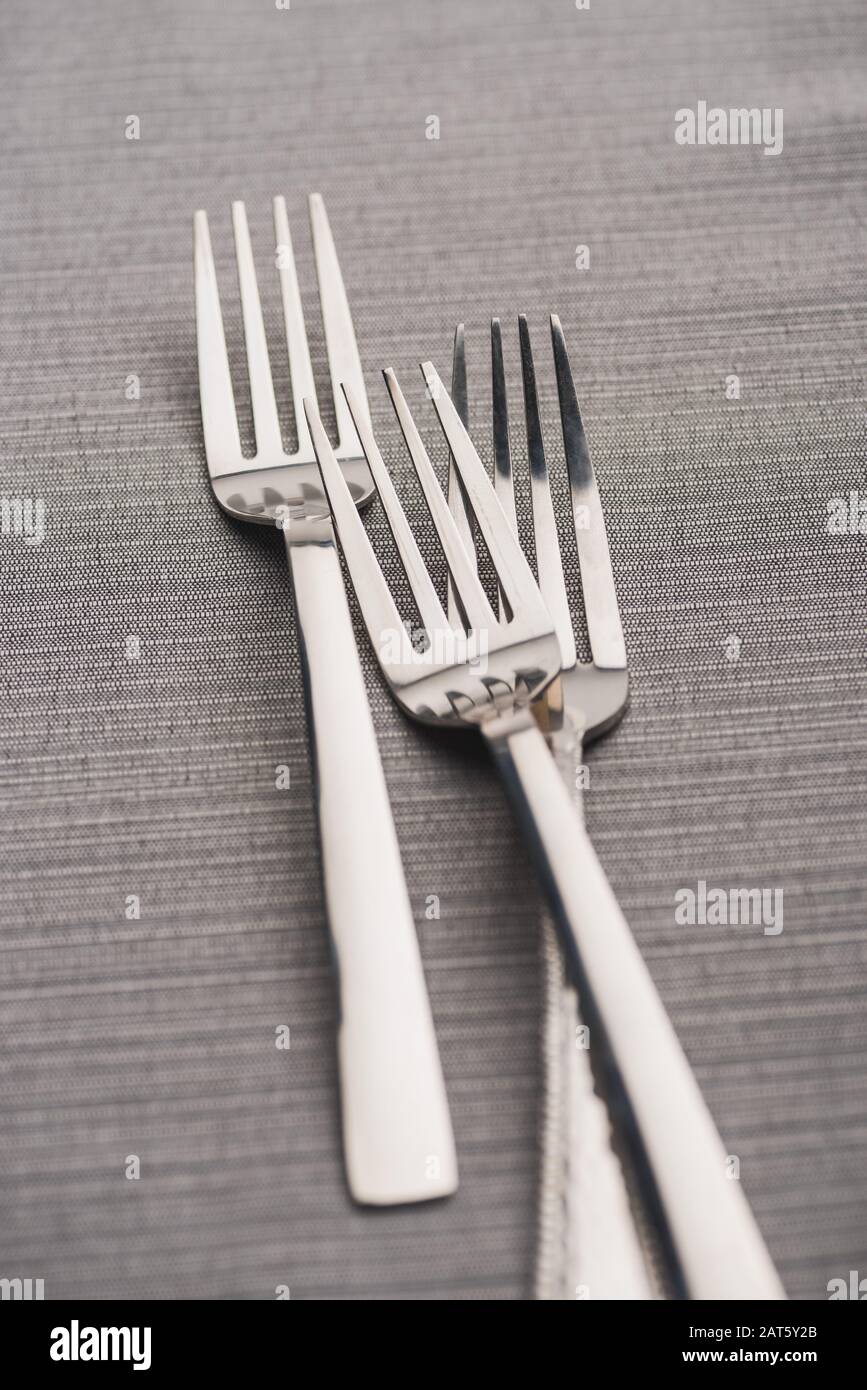 Selective focus of shiny forks on grey linen cloth Stock Photo - Alamy