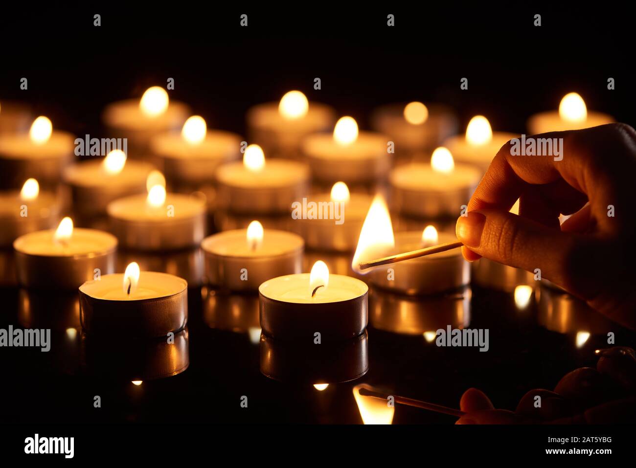selective focus of woman lighting up candle with match in dark Stock ...