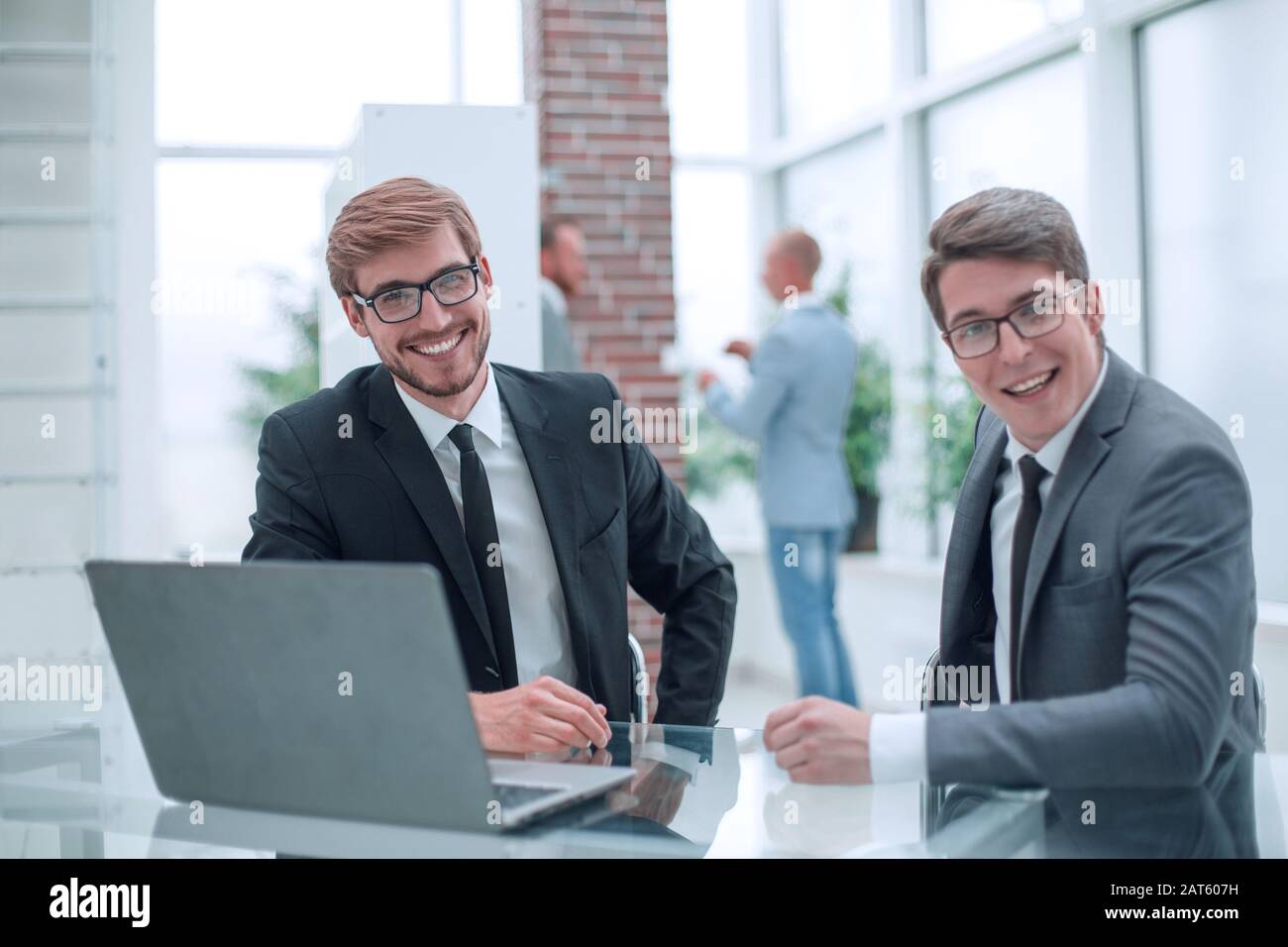 two happy businessmen sitting at an office Desk Stock Photo - Alamy