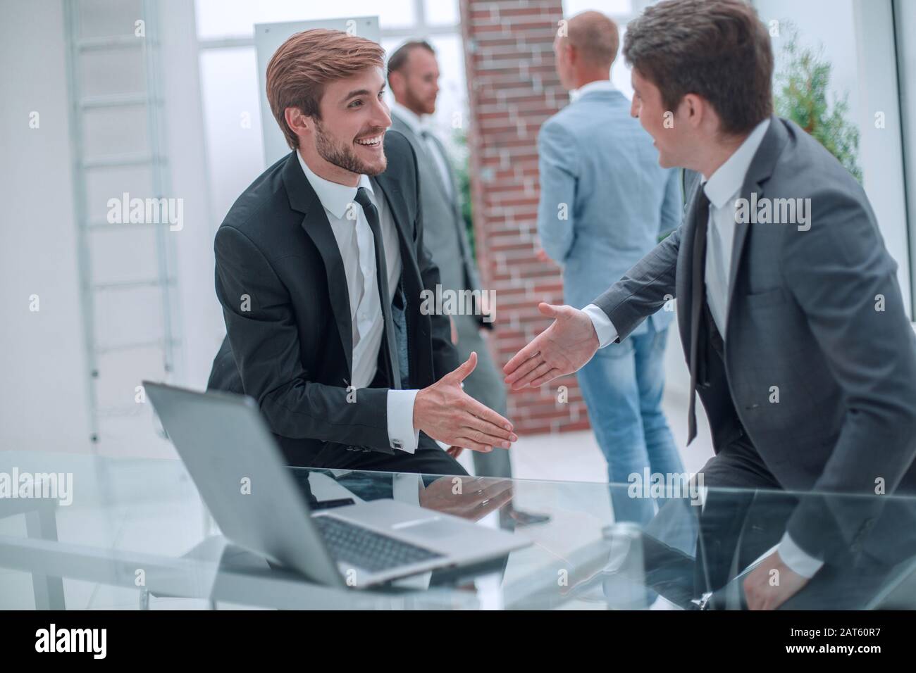 happy business people shaking hands near the desktop Stock Photo - Alamy