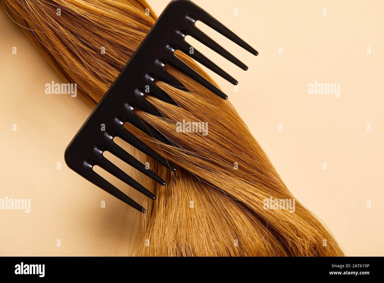 Top view of comb in twisted brown hair on beige background Stock Photo ...