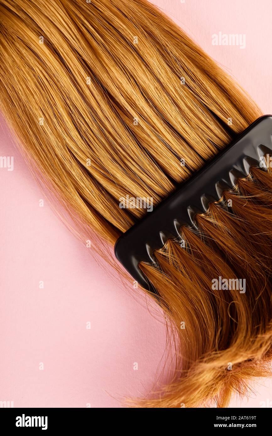 Top view of brown hair and comb on pink background Stock Photo - Alamy