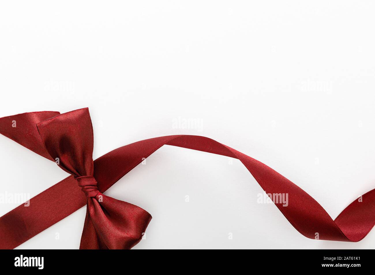 top view of satin burgundy decorative curved ribbon with bow isolated ...