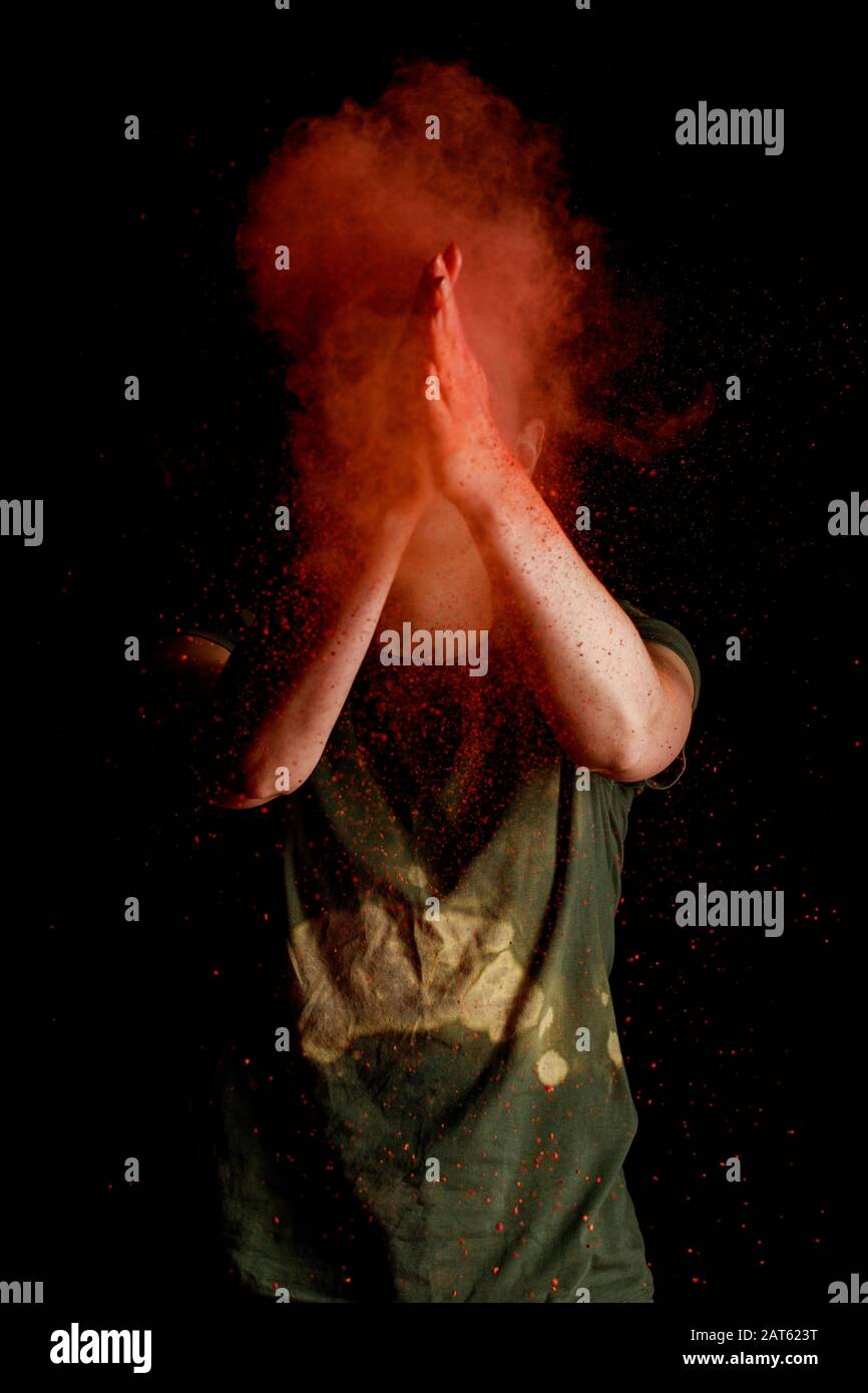 woman with orange colorful holi paint explosion in front of face on ...