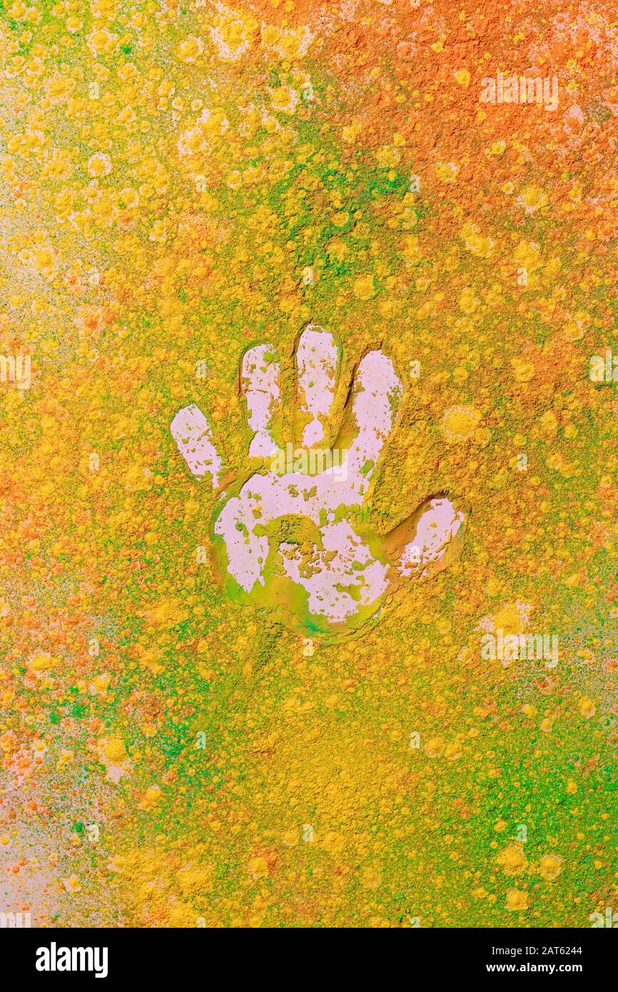 handprint on orange, yellow and green colorful holi paint explosion ...