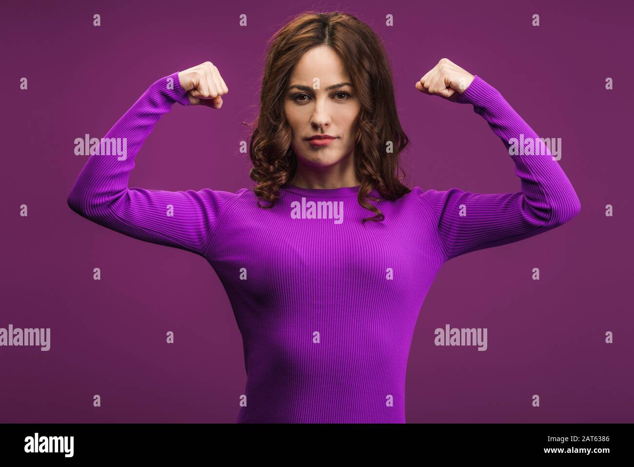 confident girl demonstrating power on purple background Stock Photo - Alamy