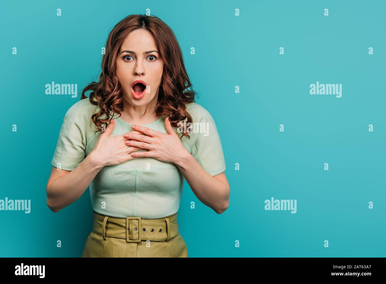 shocked woman holding hands on chest while standing with open mouth on ...