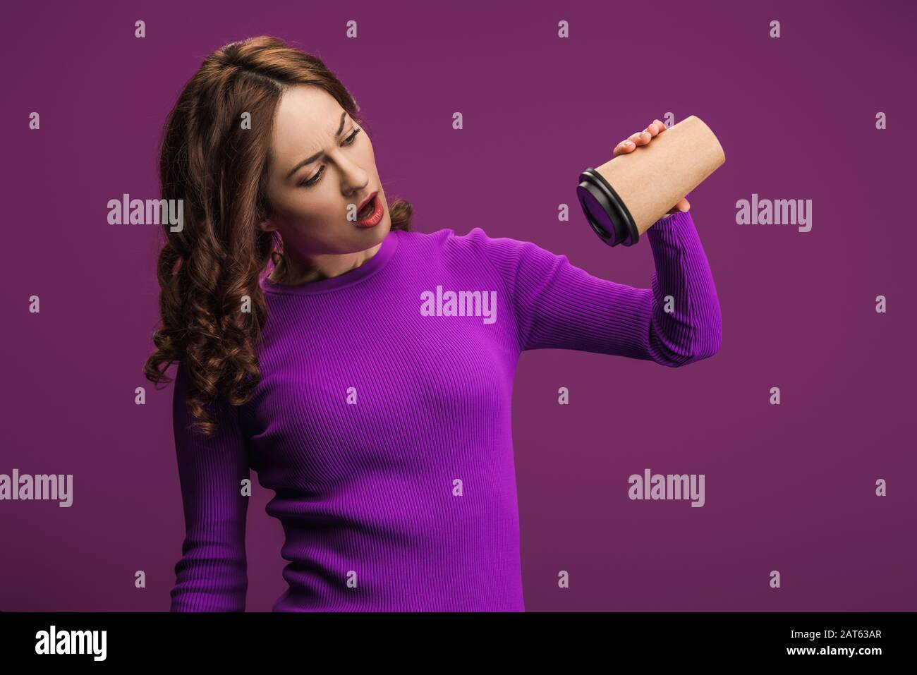 displeased girl shaking empty paper cup on purple background Stock ...