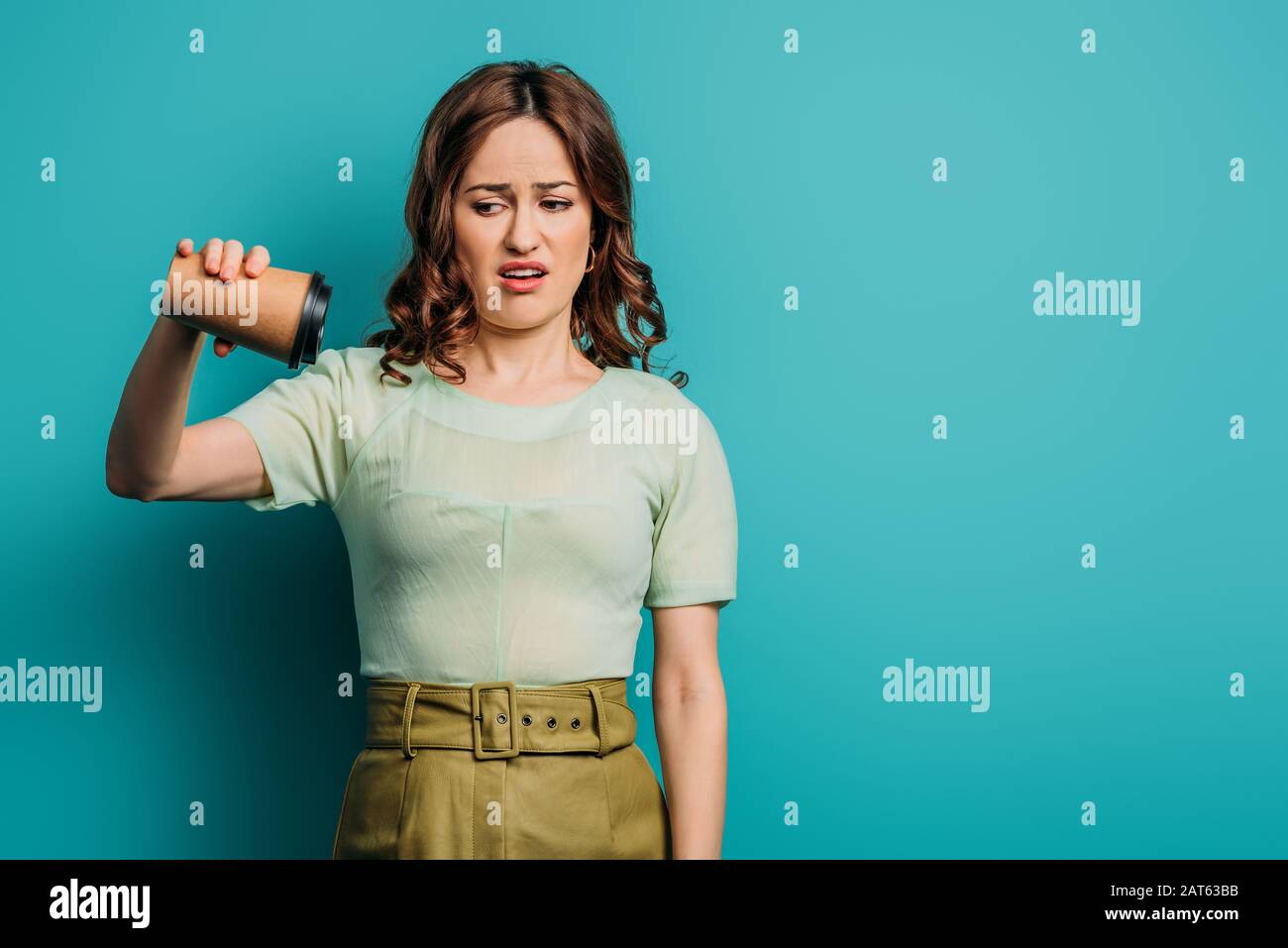 displeased woman shaking empty paper cup on blue background Stock Photo ...