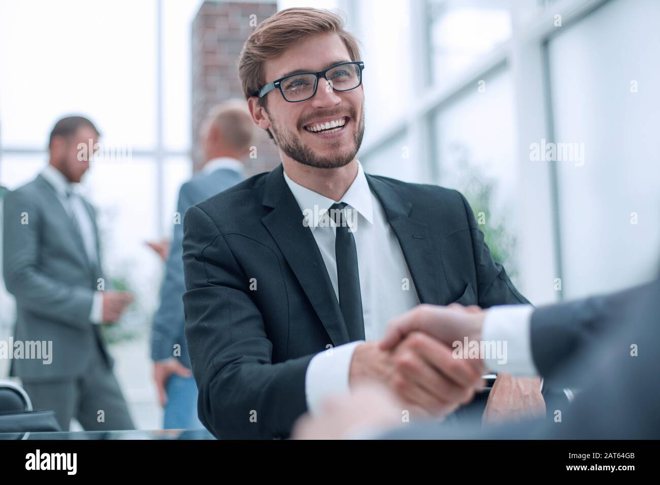 happy business partners shaking hands at the negotiating table Stock ...