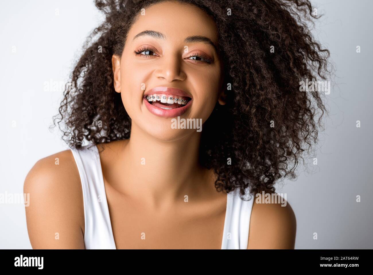 laughing african american girl with dental braces, isolated on grey ...