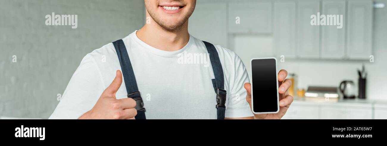 panoramic shot of happy installer holding smartphone with blank screen ...