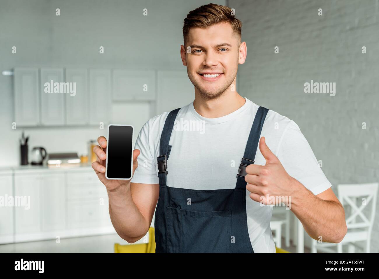 happy installer holding smartphone with blank screen and showing thumb ...