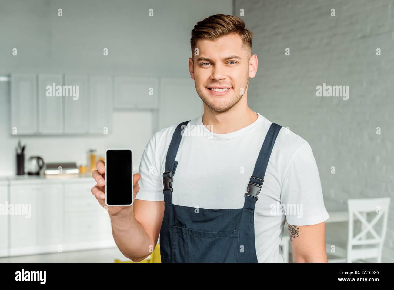 happy installer holding smartphone with blank screen and looking at ...