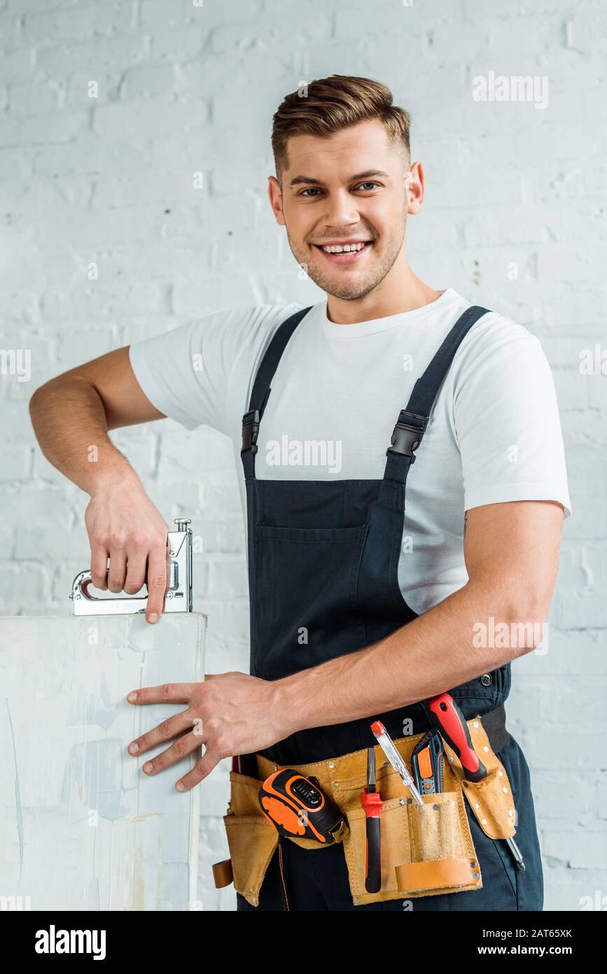 happy installer holding construction stapler near painting Stock Photo ...