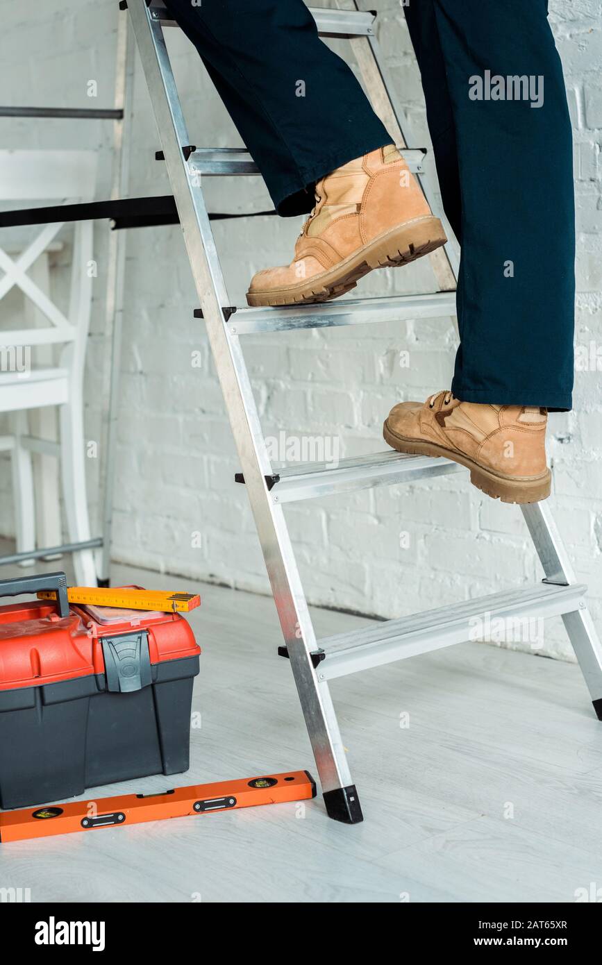 cropped view of installer climbing ladder near tool box Stock Photo - Alamy