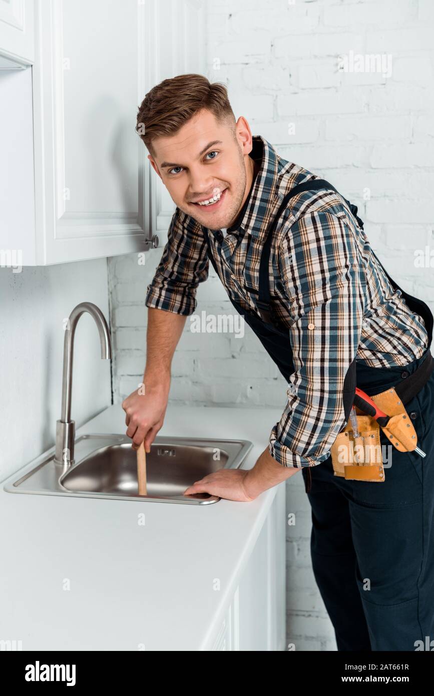 happy installer holding plunger near sink in kitchen Stock Photo - Alamy
