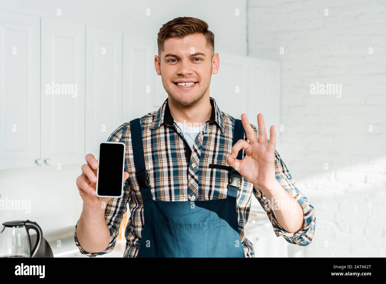 happy installer holding smartphone with blank screen and showing ok ...