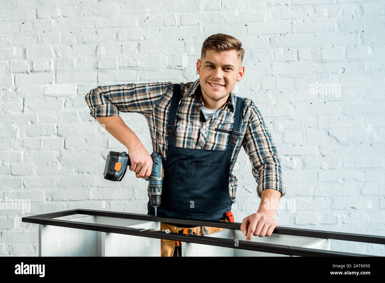 happy installer holding hammer drill near rack Stock Photo - Alamy