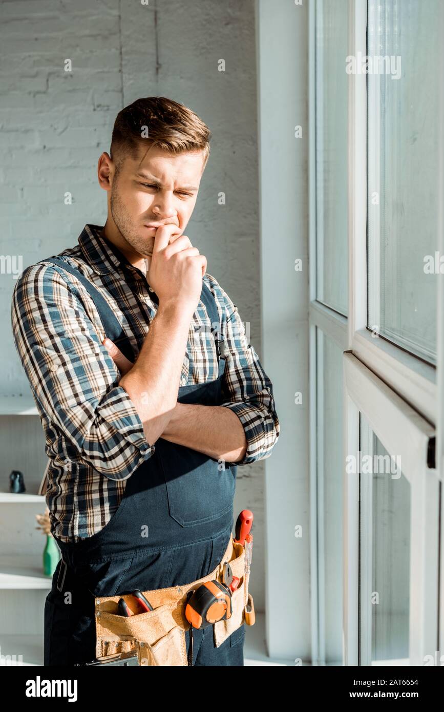 pensive installer touching face while thinking near windows Stock Photo ...