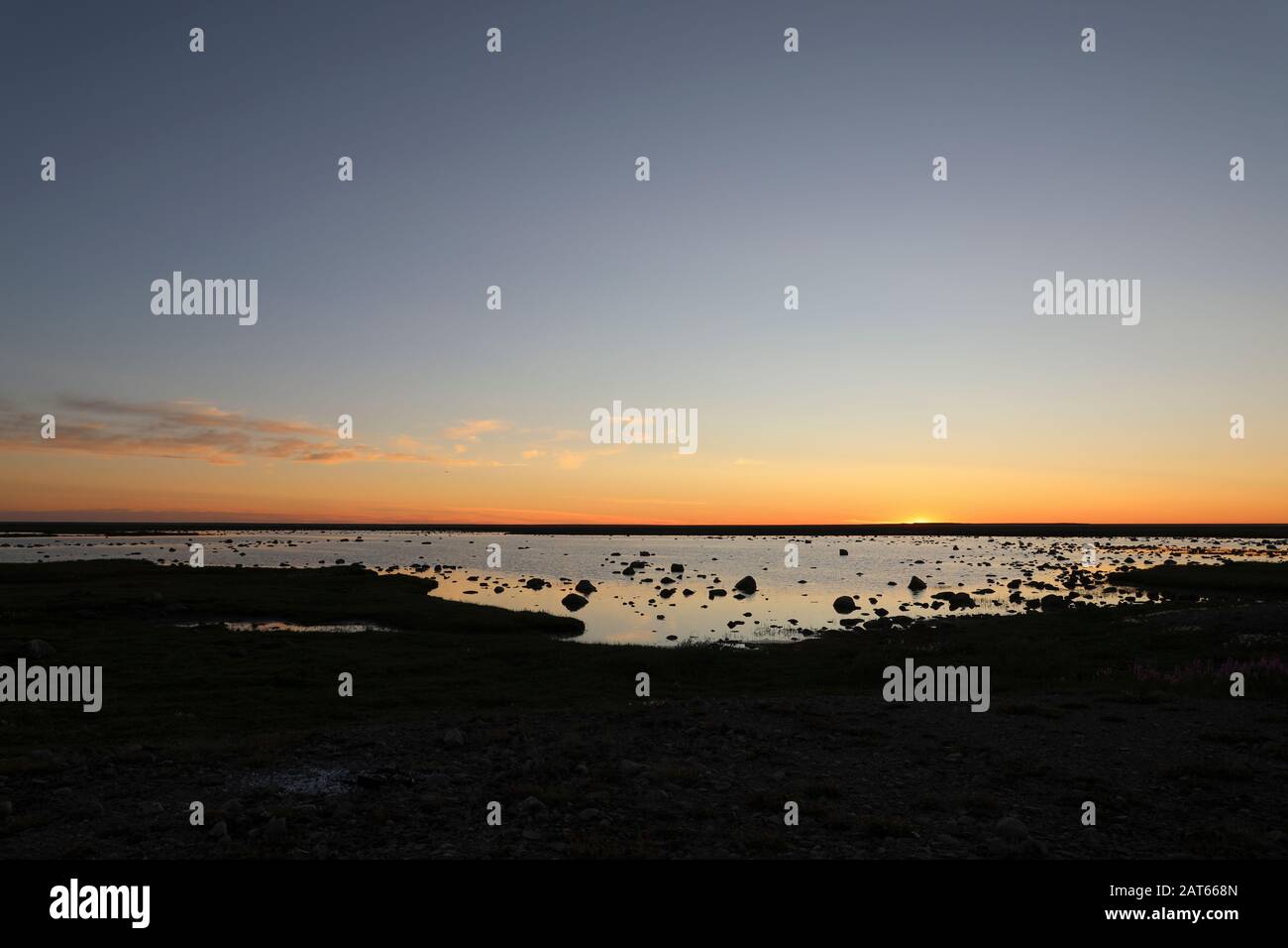 Beautiful sunset over an arctic landscape with rocks in the foreground ...