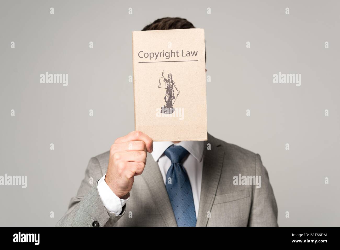 front view of lawyer obscuring face with copyright law book isolated on ...