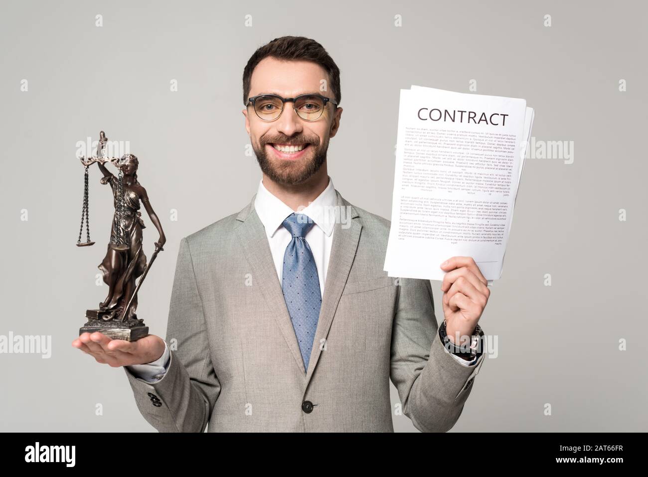 handsome lawyer holding contract and themis statue while smiling at ...