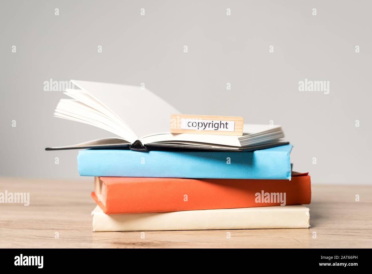 stack of books, open notebook and wooden block with word copyright on ...