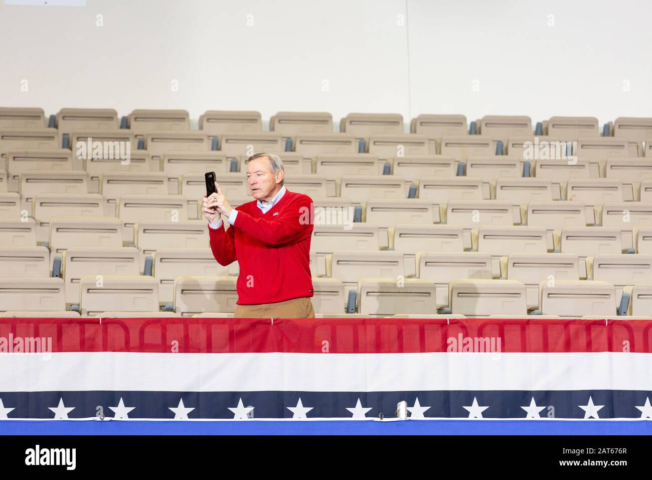 Man in empty seating area takes cell phone photograph as audience ...