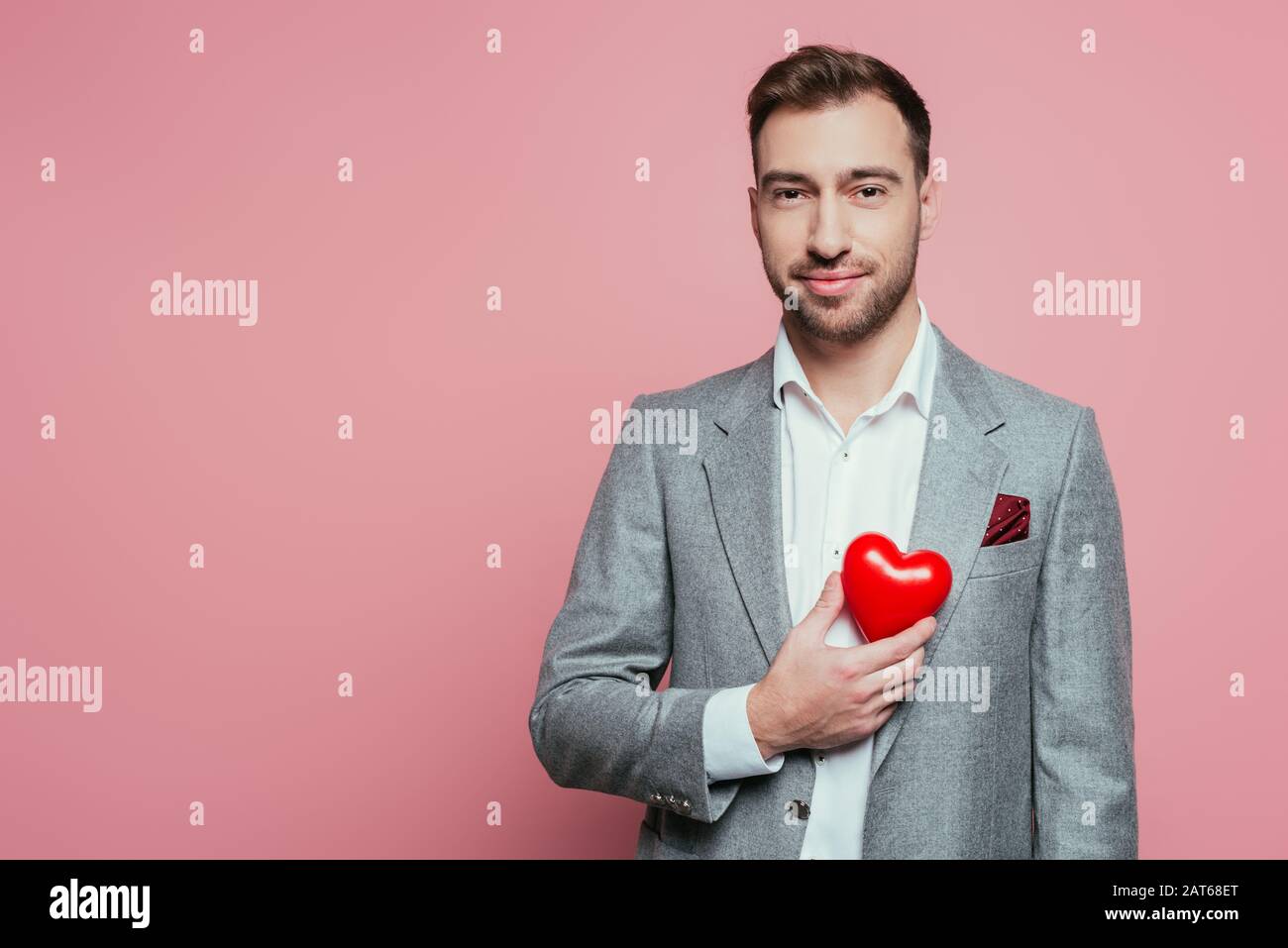 handsome man holding red heart for valentines day, isolated on pink ...