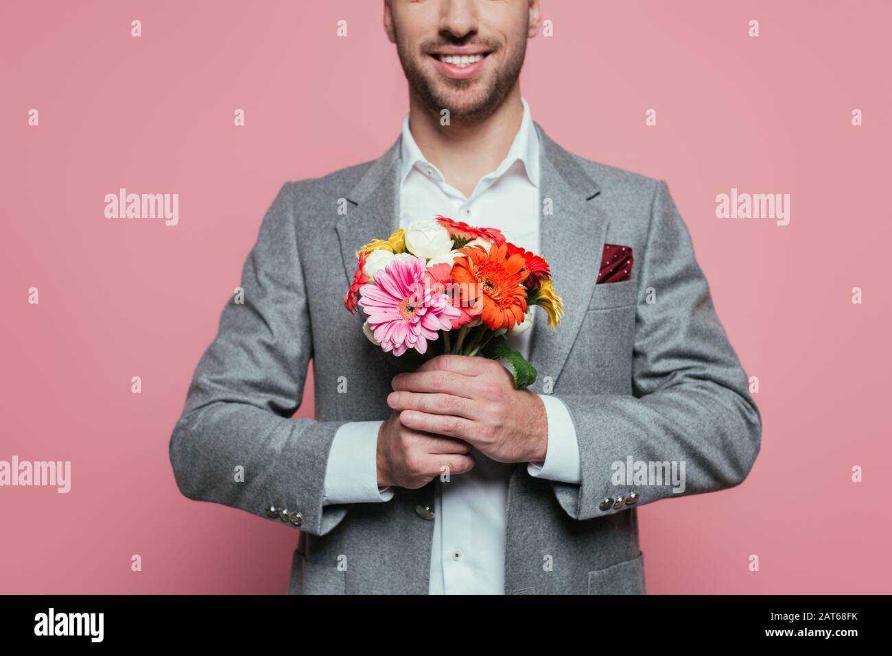 cropped view of happy man holding bouquet of flowers, isolated on pink ...