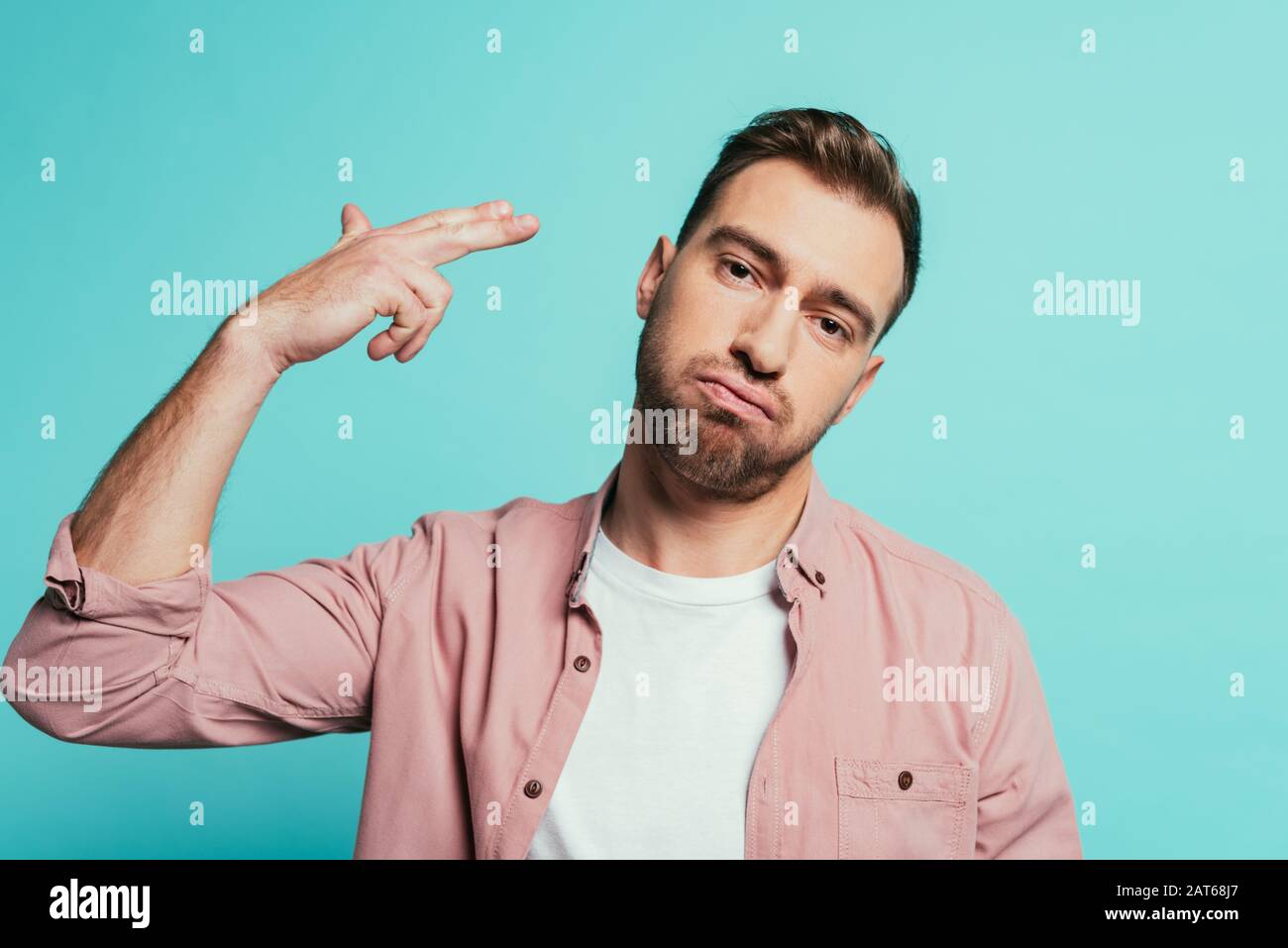 confused man with hand gun gesture, isolated on blue Stock Photo - Alamy