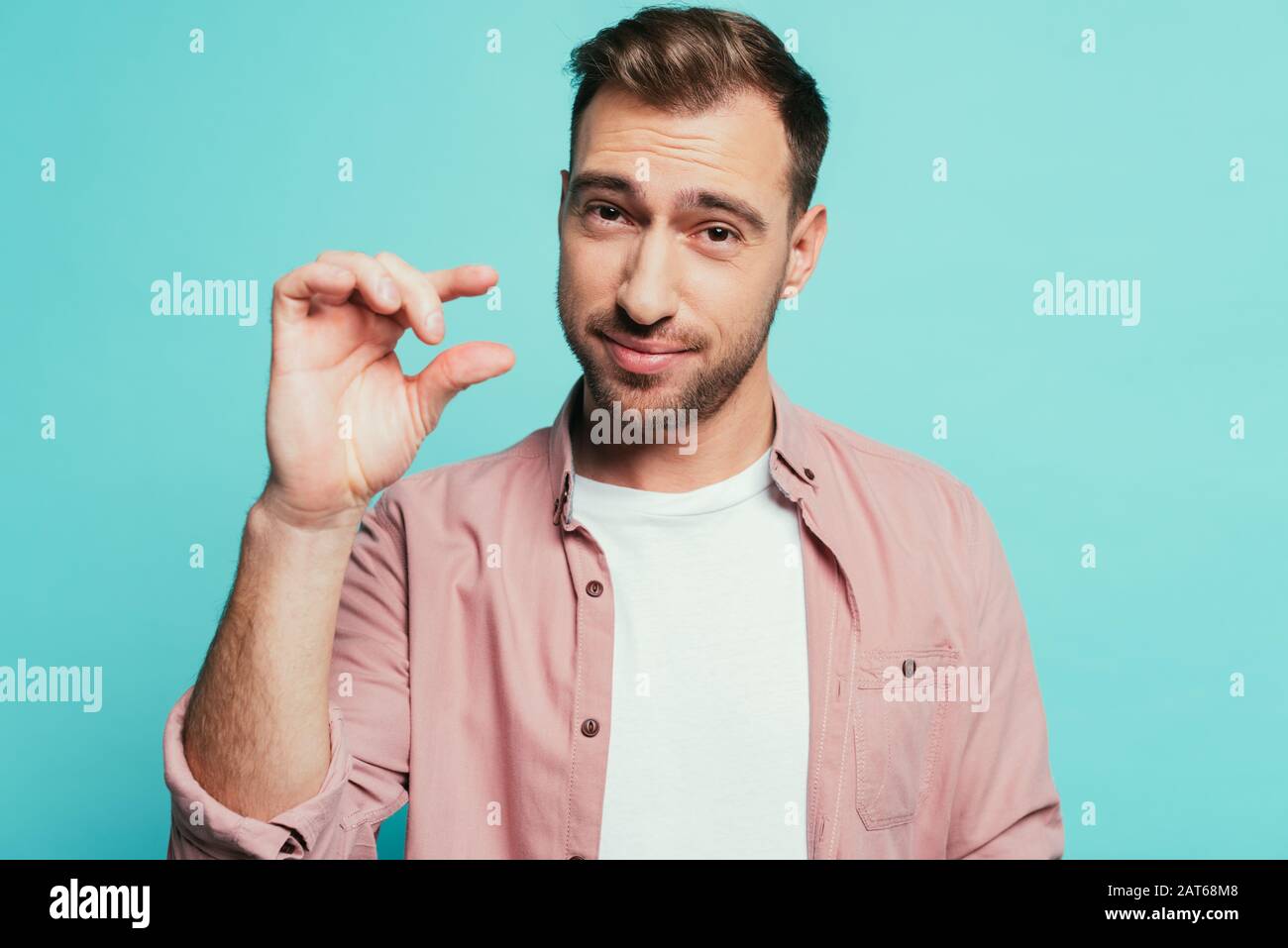 happy handsome man showing small size sign, isolated on blue Stock ...
