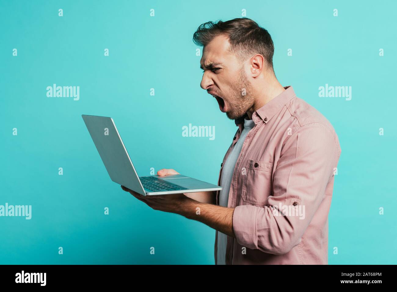 aggressive bearded man yelling at laptop, isolated on blue Stock Photo ...