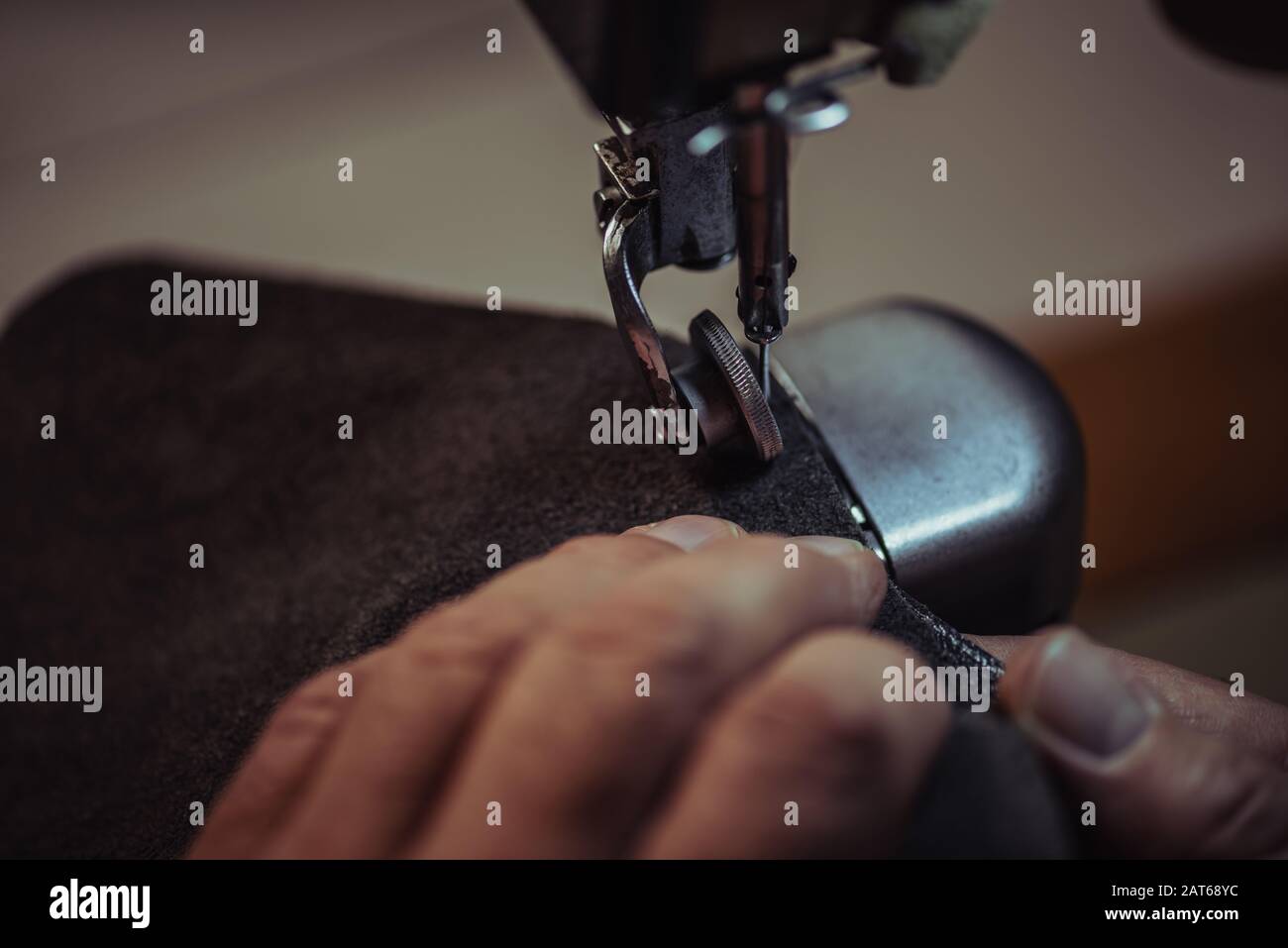 partial view of shoemaker sewing genuine leather on sewing machine ...