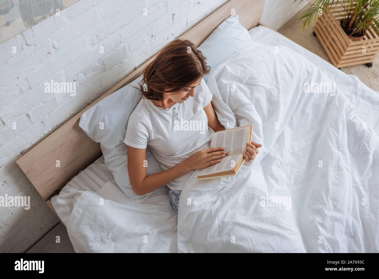 top view of happy woman reading book while chilling in bed Stock Photo ...