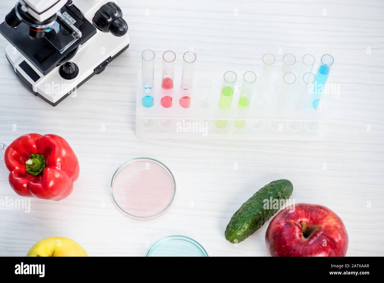 high angle view of microscope, fruit, vegetables, test tubes and petri ...
