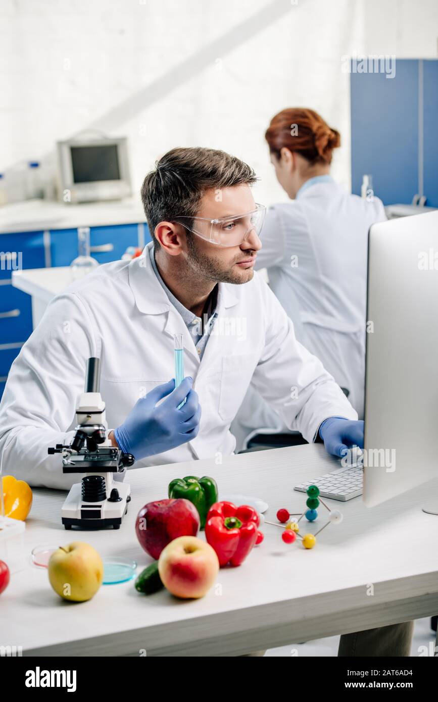 molecular nutritionist holding test tube and using computer in lab ...